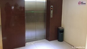 Um elevador com placa de proibido fumar, um cesto de lixo e um visor digital.