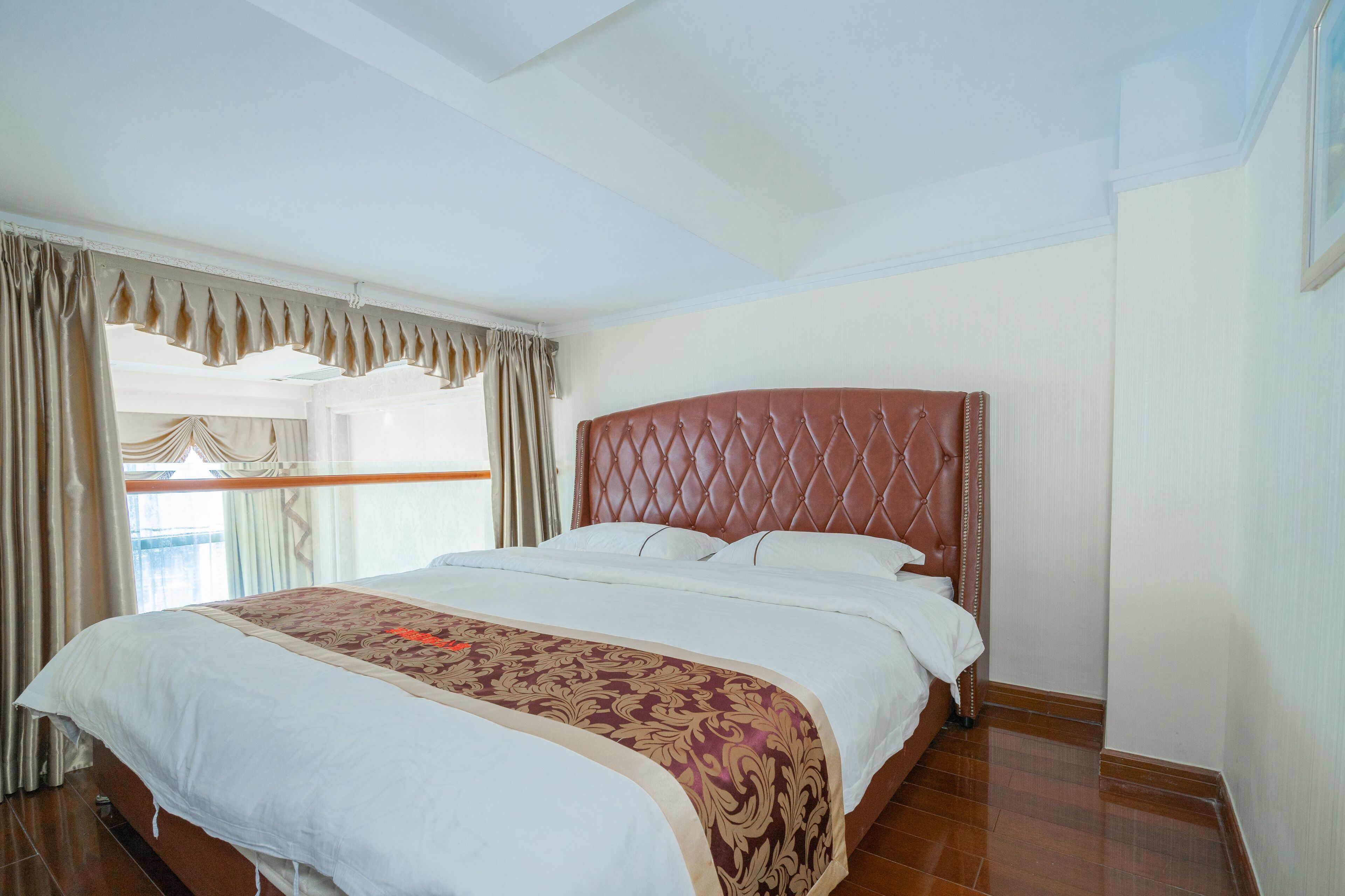 Quarto de hotel com uma cama grande, janela com cortinas e vista para o exterior.