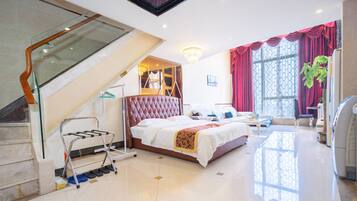 Quarto de hotel com uma cama grande, escadas de vidro, um candelabro e vista para o exterior por grandes janelas.
