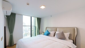 Quarto de hotel com uma cama grande, janela com cortinas, luminária no teto e ar-condicionado fixado na parede.