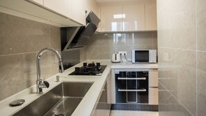 Uma cozinha moderna com pia de aço inoxidável, micro-ondas embutido e lava-louças.