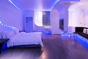 Um quarto moderno com uma cama, uma mesinha, uma televisão e um detalhe único na parede.