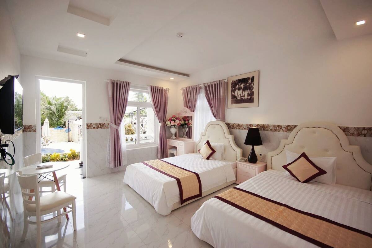 Quarto de hotel com duas camas, uma escrivaninha e uma cadeira.