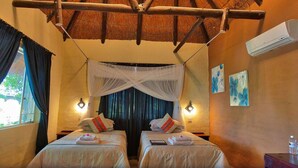 Quarto com duas camas, mosquiteiro e ar condicionado.