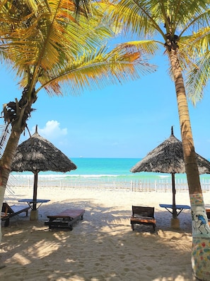 Na praia, praia de areia branca, espreguiçadeiras, guarda-sóis de praia 