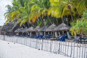 Na praia, praia de areia branca, espreguiçadeiras, guarda-sóis de praia 