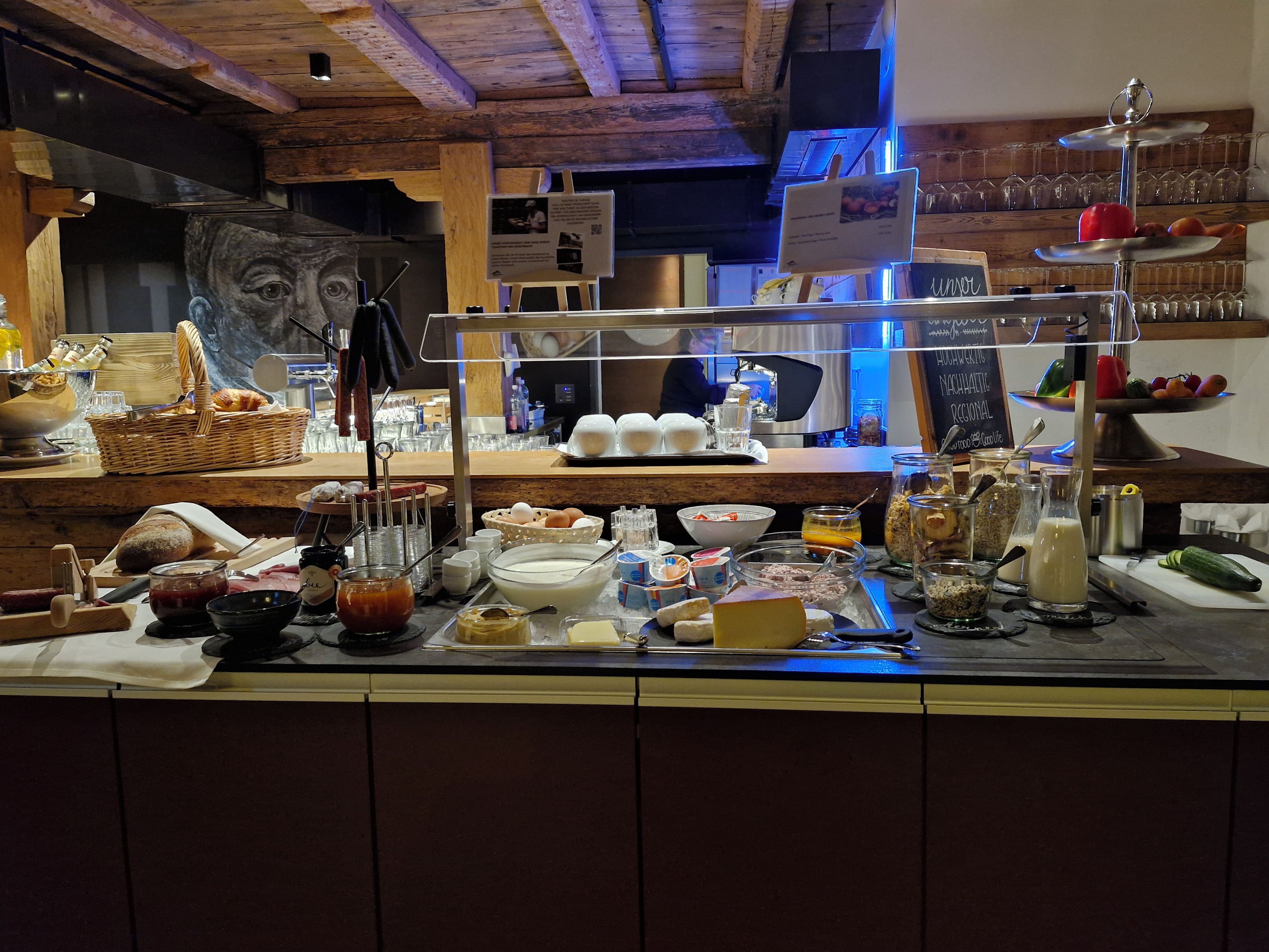 Disposição de buffet com diversos alimentos e exposição de vinhos.