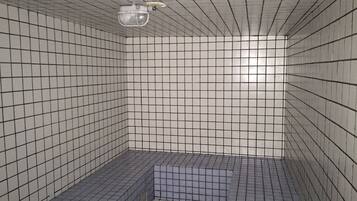 Um banheiro com revestimento de azulejos, área de chuveiro e vaso sanitário.