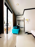 Quarto de hotel com varanda, sofá, cama, lixeira e unidade de ar condicionado.