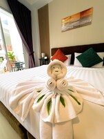 Quarto de hotel com cama bem arrumada, vista para a varanda e um quadro na parede.