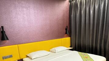 Quarto de hotel com uma cama, um telefone e uma luminária na mesa de cabeceira.