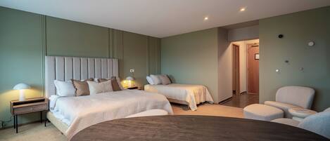 Quarto de hotel com duas camas, uma mesa de madeira e uma cadeira.
