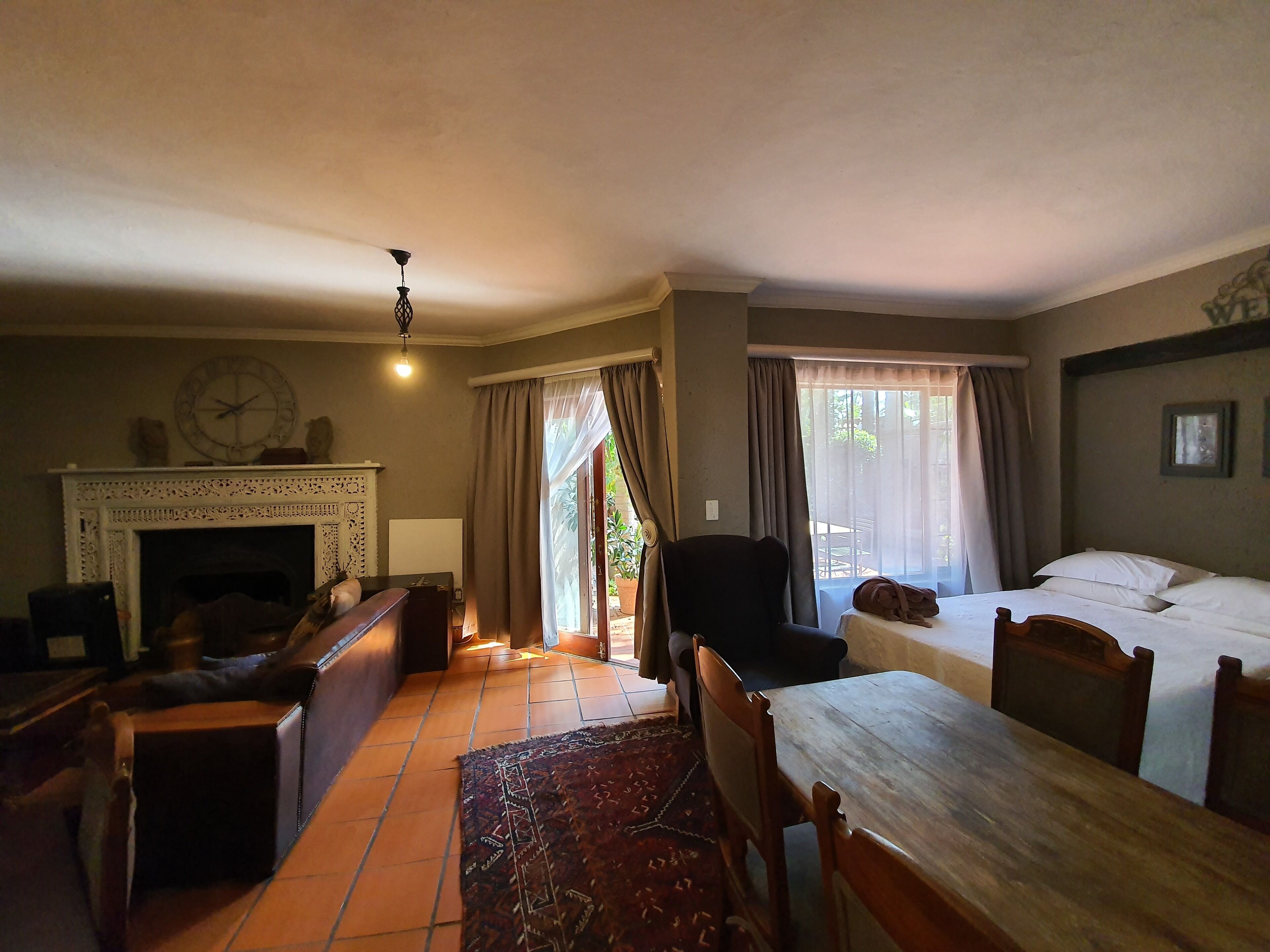 Um quarto com lareira, uma mesa de jantar com cadeiras, uma cama e uma janela grande com cortinas.