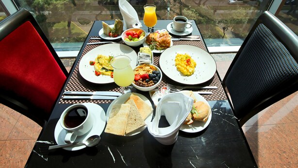 Uma mesa de café da manhã com pratos de comida, uma xícara de café e um copo de suco de laranja.