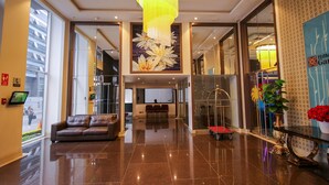 Um hall amplo com um grande lustre, área de estar e balcão de recepção.