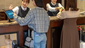 Uma área de recepção com balcão, tablet digital e mesa de check-in.