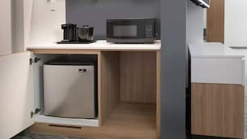 Uma cozinha compacta equipada com micro-ondas, cafeteira e mini-geladeira.