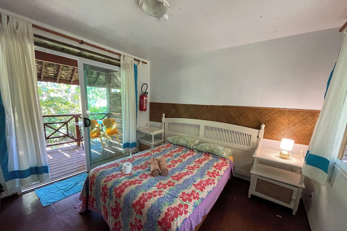 Um quarto com uma cama, uma mesa de cabeceira, uma cadeira e vista para o exterior.