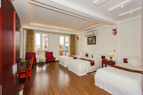 Quarto de hotel com duas camas, uma mesa de jantar e uma poltrona vermelha.