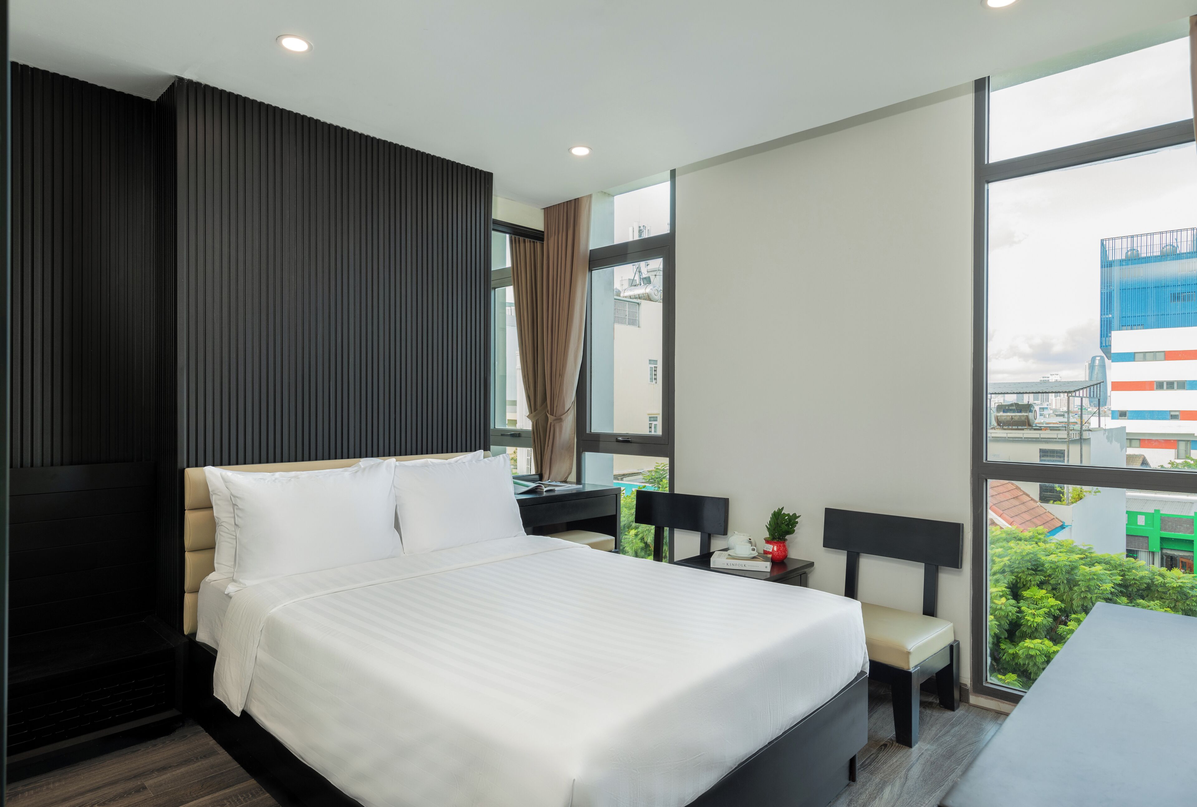 Quarto de hotel moderno com uma cama grande, uma escrivaninha e vista para a cidade.