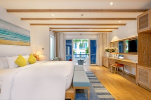 Quarto de hotel moderno com uma cama grande, uma escrivaninha e vista para a varanda.
