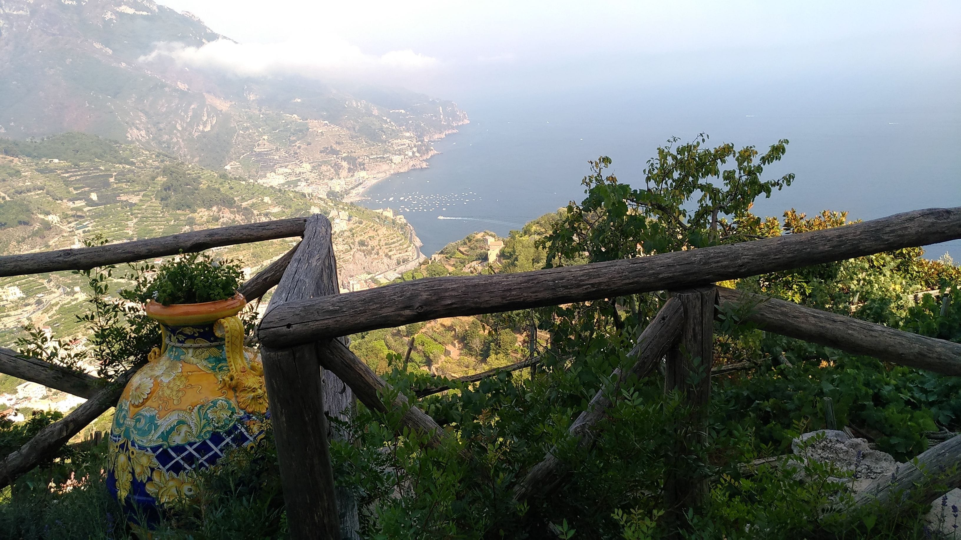 Vista panorâmica de um ponto alto sobre uma paisagem costeira com campos em socalcos e uma cerca de madeira.