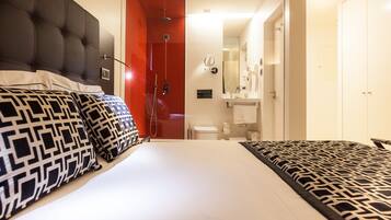 Quarto de hotel com uma cama grande, uma porta vermelha que dá para o banheiro e um guarda-roupa branco.