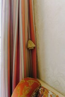 Canto de um quarto com cortinas listradas e papel de parede estampado.