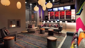 Uma área de estar moderna com lareira, assentos confortáveis e um bar com letreiro neon.
