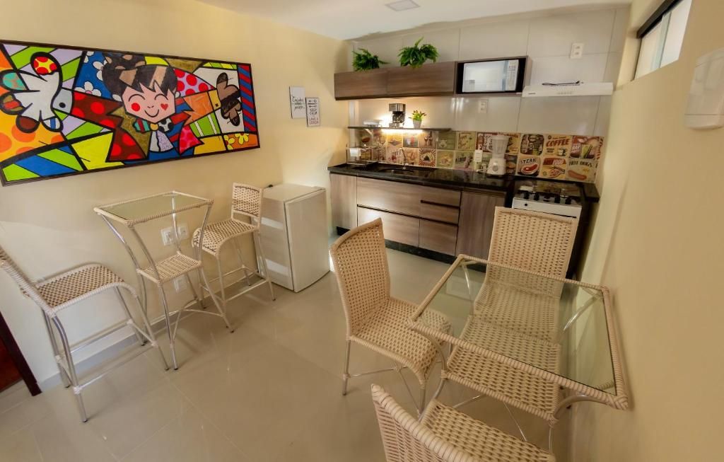 Cozinha compacta com área de refeições, equipada com micro-ondas, cafeteira e azulejos decorativos.