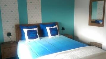 Quarto com uma cama, duas mesas de cabeceira e um espelho na parede.