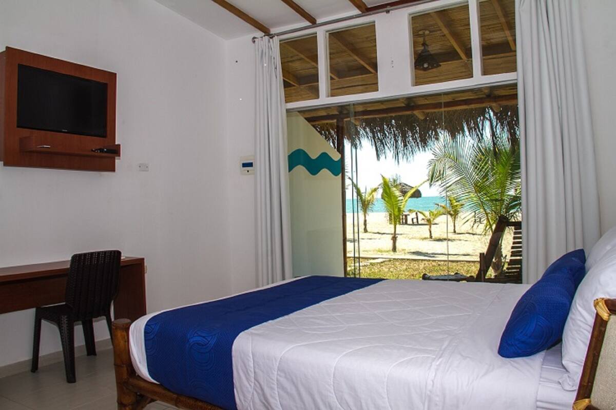 Quarto com cama, escrivaninha e televisão.