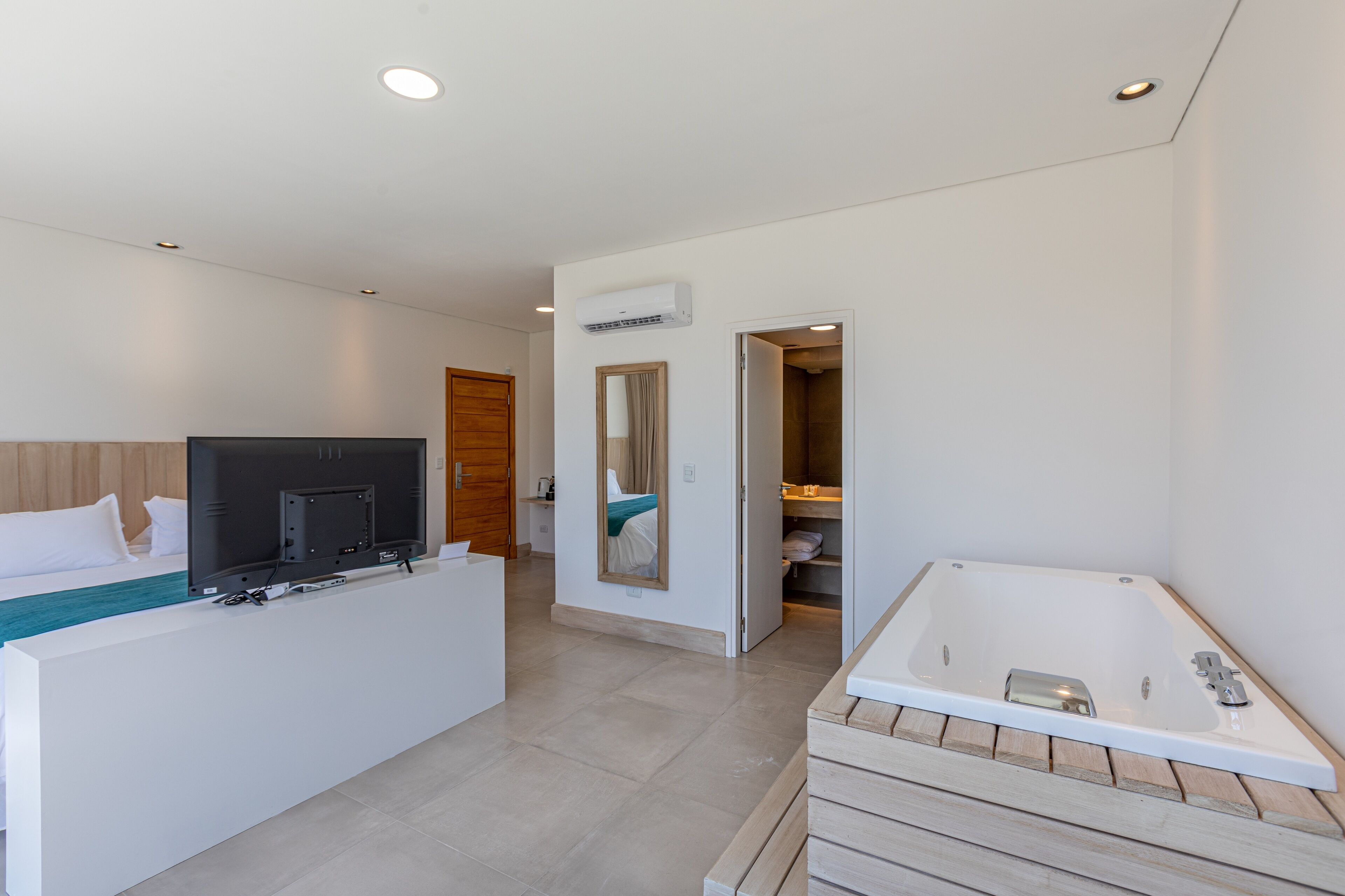 Quarto de hotel moderno com televisão de tela plana, uma banheira grande e um closet espaçoso.