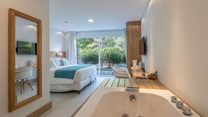 Quarto moderno com uma cama grande, uma escrivaninha de madeira, uma televisão e um banheiro com banheira.