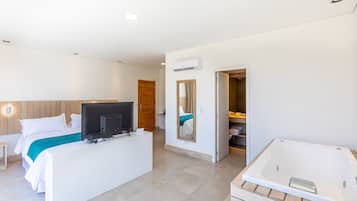 Quarto de hotel moderno com cama, secretária com televisão, banheira grande e closet espaçoso.