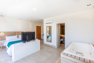 Quarto de hotel moderno com cama, secretária com televisão, banheira grande e closet espaçoso.