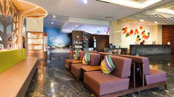 Um lobby moderno com balcão de recepção, área de estar e um painel decorativo.