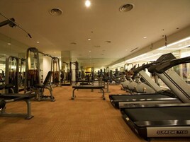 Academia com esteiras, máquinas de musculação e pesos livres.