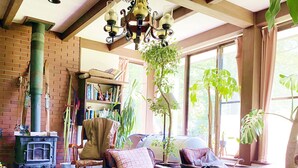 Uma sala de estar aconchegante com lareira, estantes de livros, assentos confortáveis e grandes janelas que permitem a entrada de luz natural.