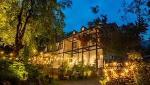 Um edifício tradicional com entrada para um jardim, luzes de festa e uma placa.