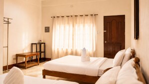 Quarto de hotel com cama, mesa de cabeceira e cabideiro.