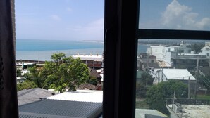 Vista da janela com vista para uma área costeira, prédios e um corpo d'água.