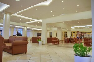 Um hall amplo com teto alto, várias áreas de estar e uma planta central.