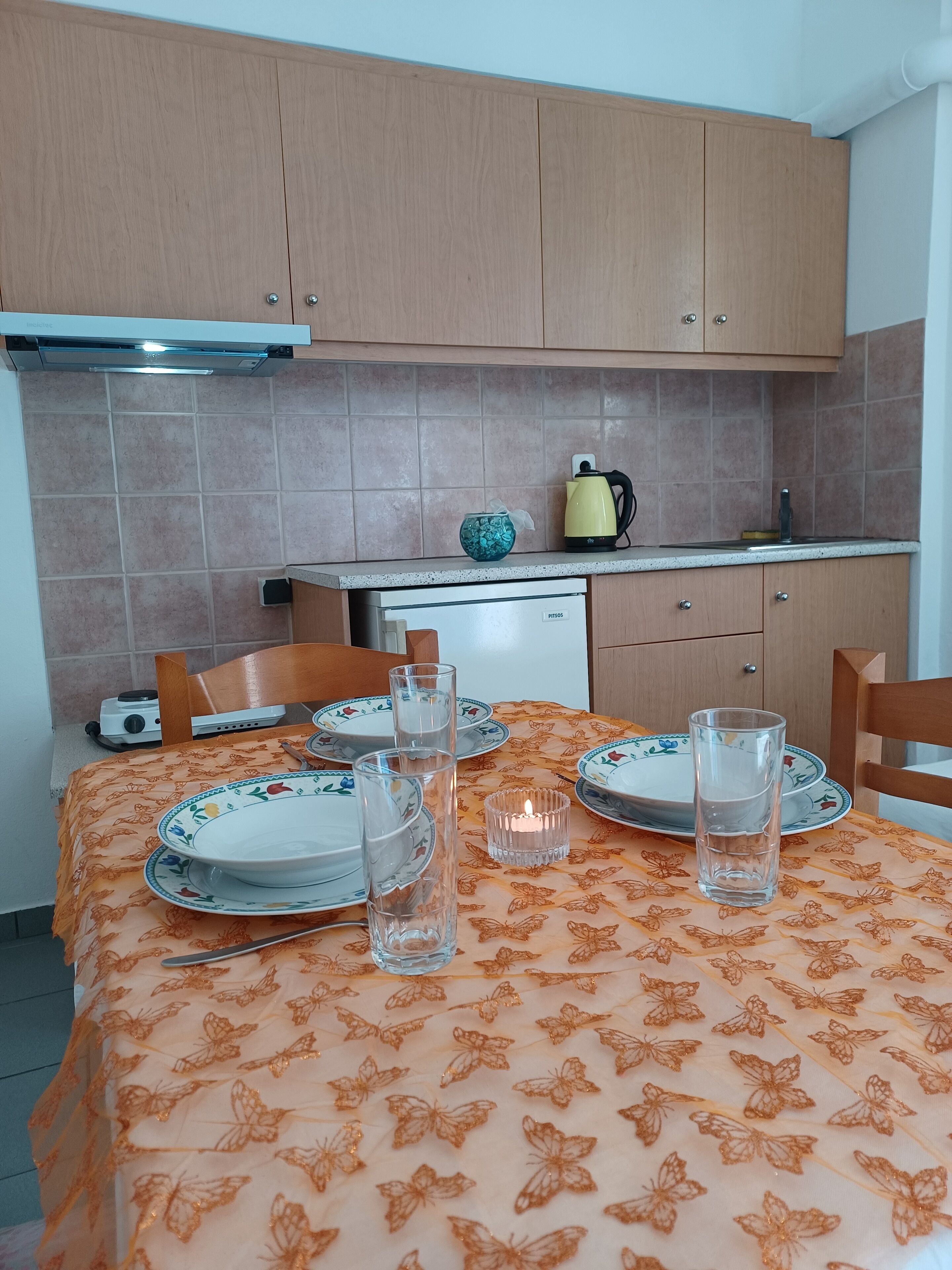 Uma cozinha com armários de madeira, fogão a gás e uma mesa posta com pratos e copos.