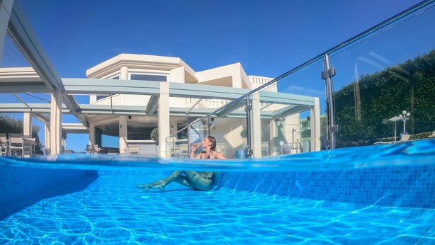 Uma piscina com uma pessoa relaxando na borda.