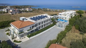 Um hotel moderno com piscina no terraço, painéis solares e vista para o mar.