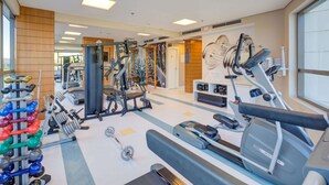 Uma academia com diversos equipamentos de exercícios, incluindo esteiras, aparelhos de musculação e pesos livres.