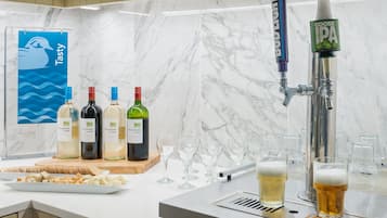Uma área de bar com uma torneira de cerveja identificada como 'BOD LIGHT' e 'GOOSE IPA', um letreiro com a palavra 'Tasty' e várias garrafas de vinho.