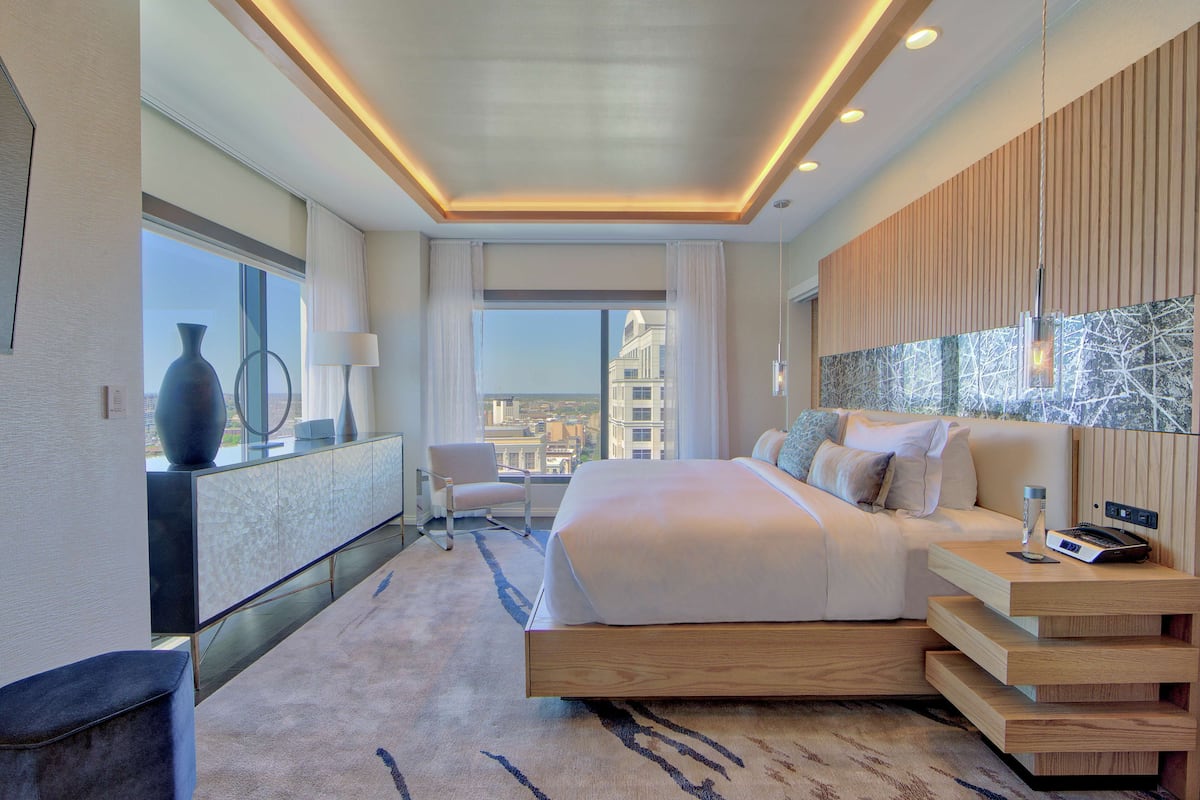 Quarto de hotel moderno com uma cama grande, uma escrivaninha e vista para a cidade.