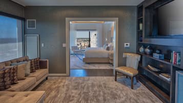 Quarto de hotel moderno com uma cama grande, um sofá, uma cadeira e uma estante.